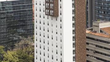 Um hotel moderno com fachada branca, vários andares e um jardim no terraço.