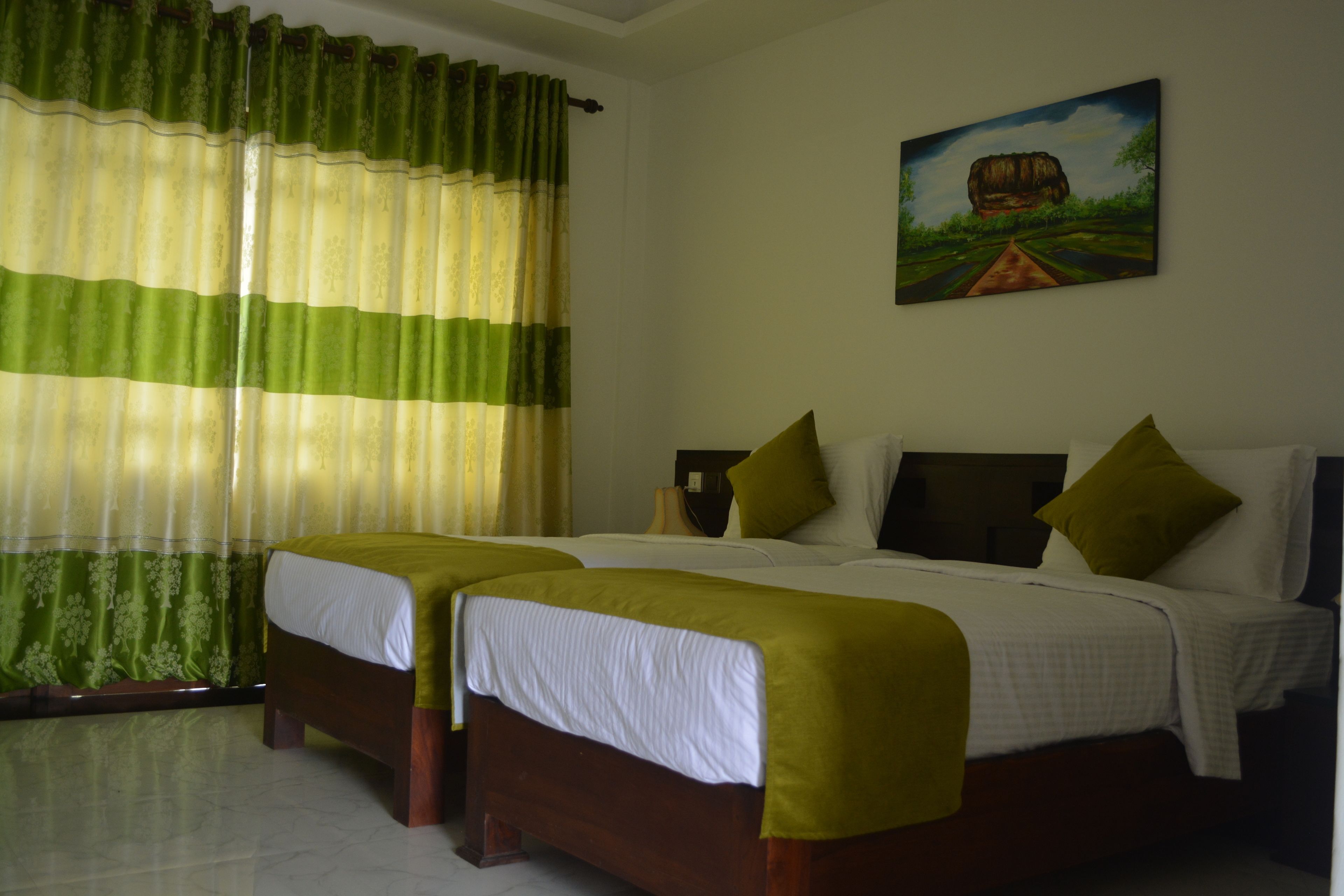 Quarto de hotel com duas camas, um quadro na parede e cortinas verdes.