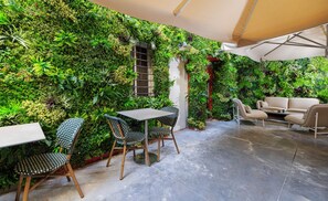Um pátio interno com parede verde, área de estar e uma mesa.