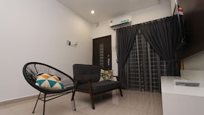 Uma sala de estar moderna com uma cadeira preta, um sofá e um console branco.