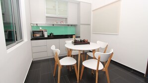 Cozinha moderna com armários brancos, bancada preta e mesa de jantar redonda com cadeiras brancas.