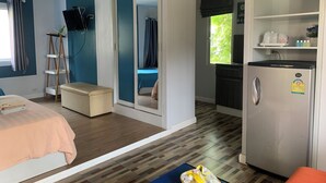 Quarto de hotel com cama, pequena área de estar, guarda-roupa, cozinha compacta e janela com vista.