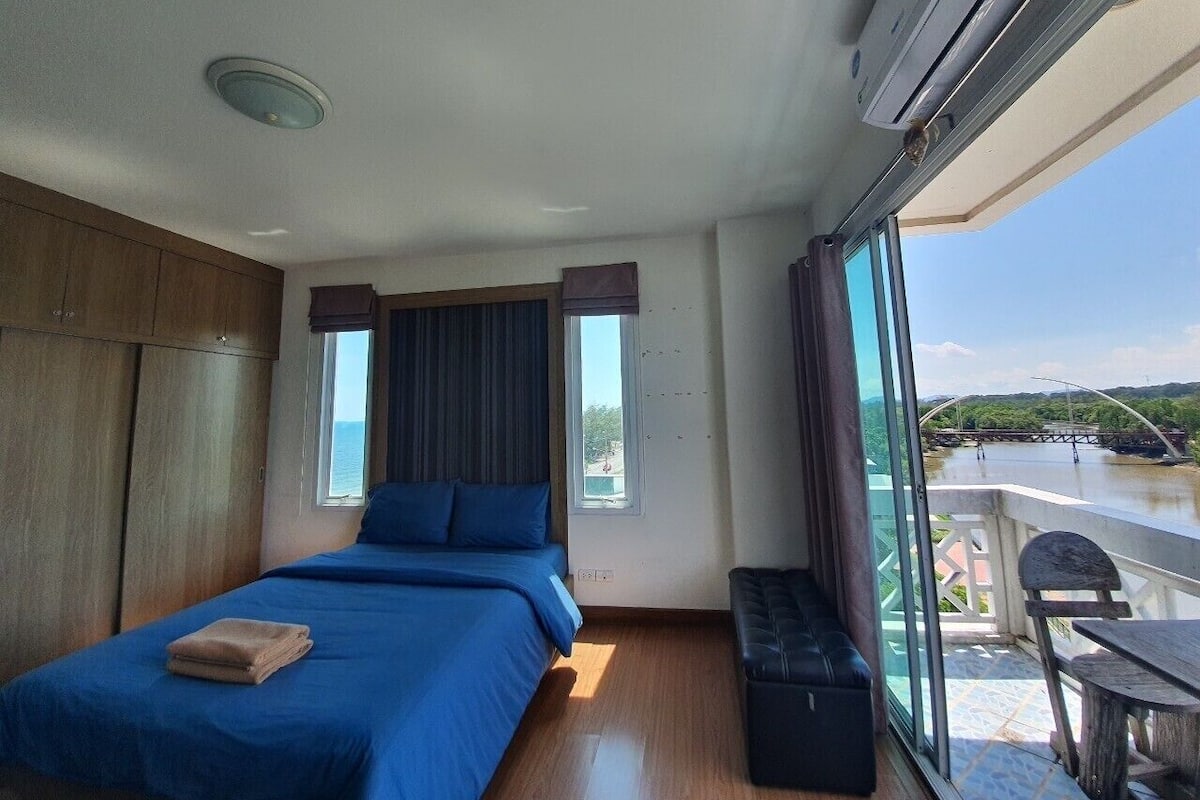 Quarto com cama, janela, varanda e vista para um rio.