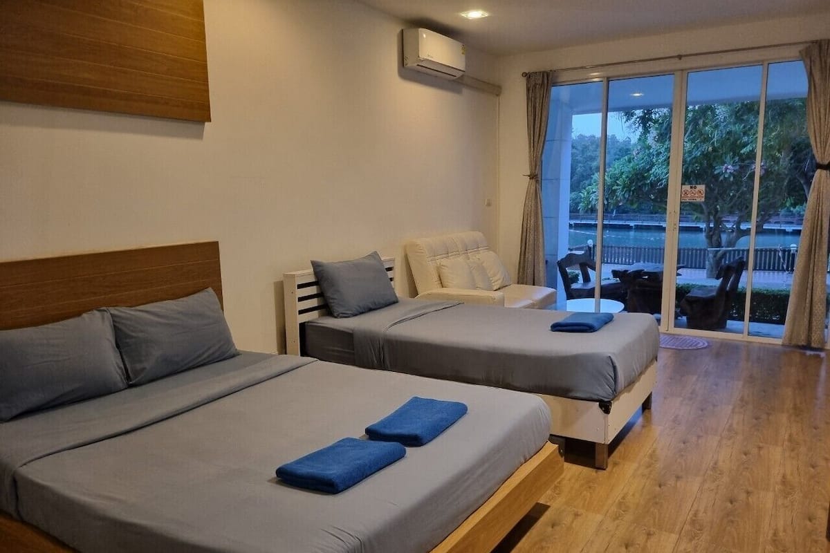 Quarto de hotel com duas camas, varanda e vista para uma ponte.