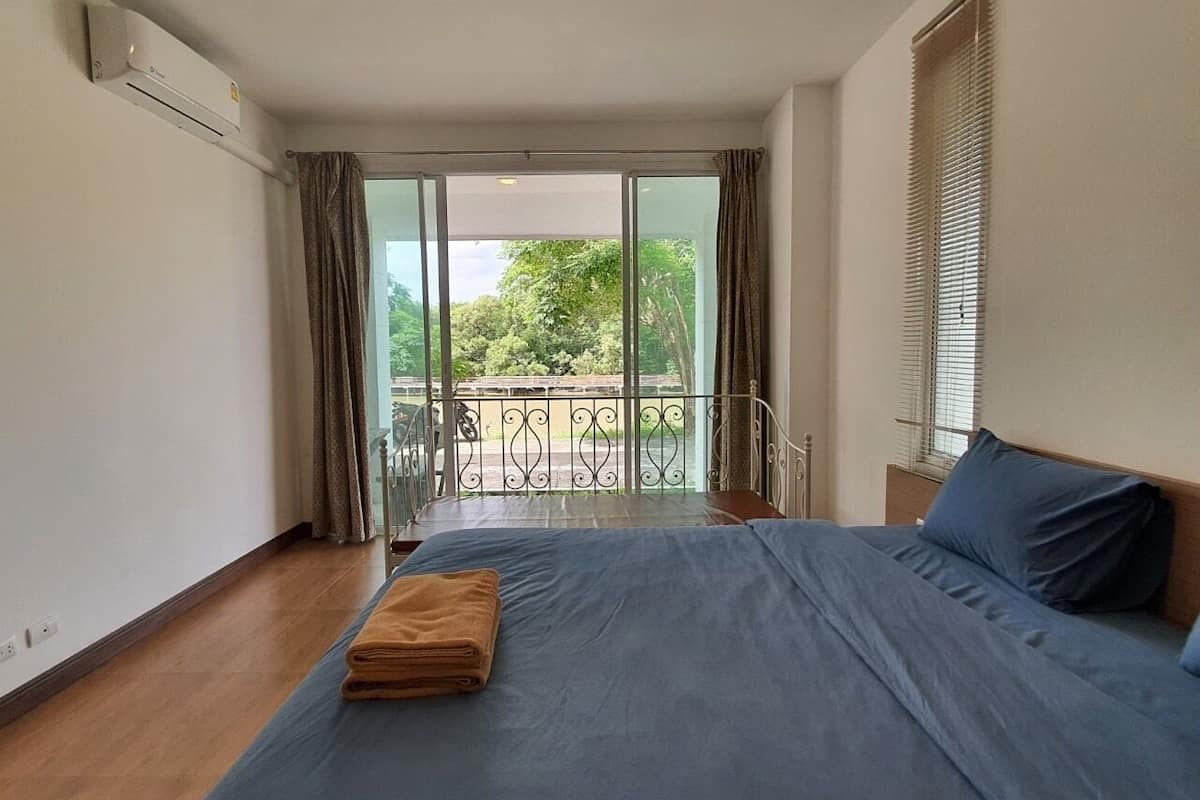 Um quarto com cama, varanda com guarda-corpo e ar condicionado.
