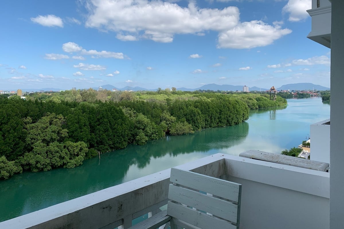 Um rio com vegetação densa em uma margem e um céu azul claro com algumas nuvens.
