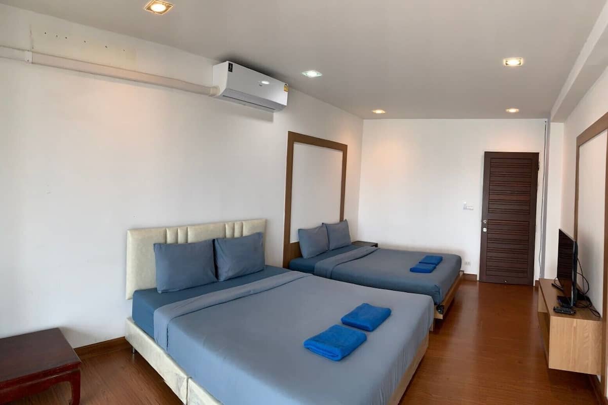 Quarto de hotel com duas camas, uma televisão e aparelho de ar condicionado.