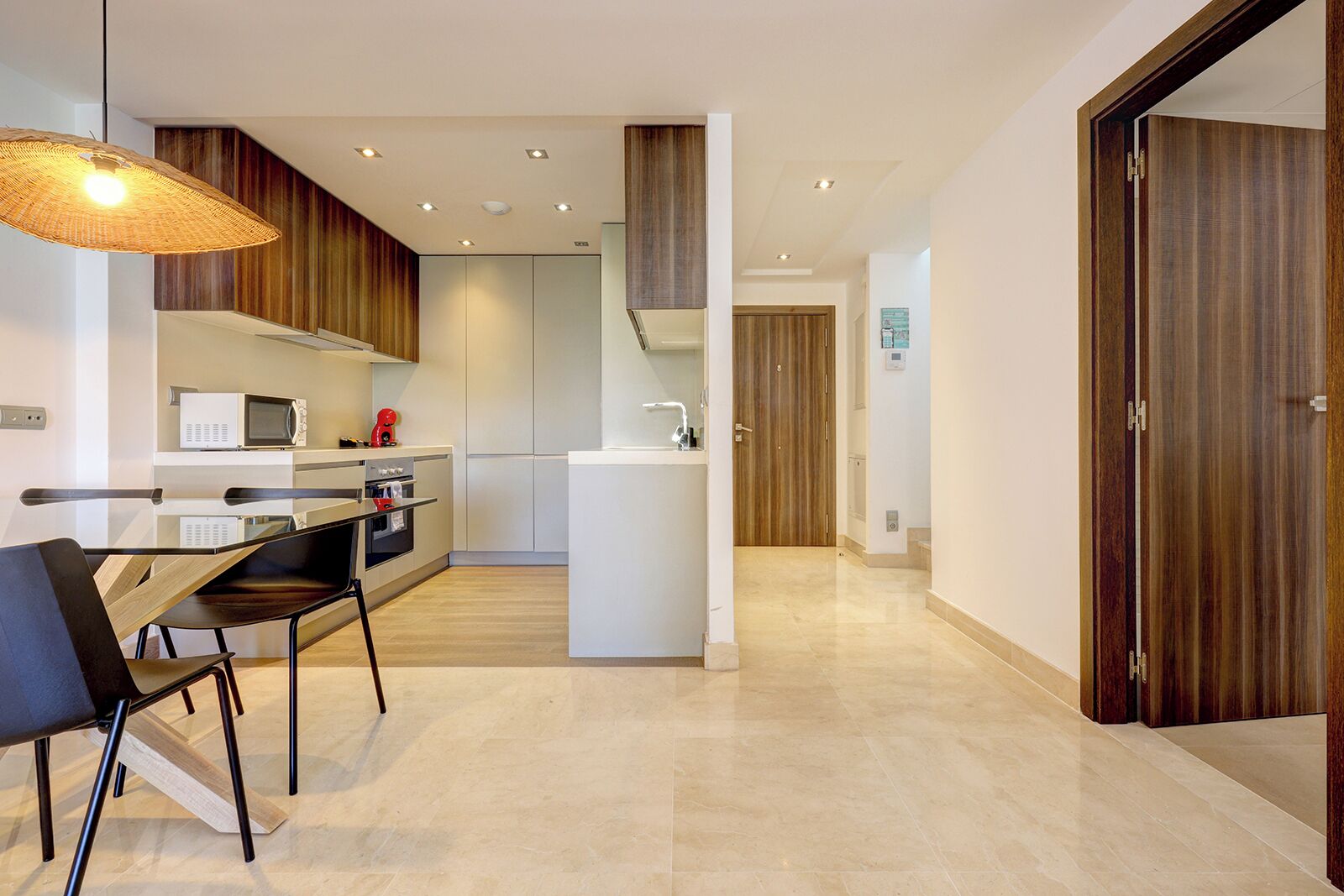 Cozinha moderna com área de jantar, incluindo uma ilha central, eletrodomésticos embutidos e luminária pendente.