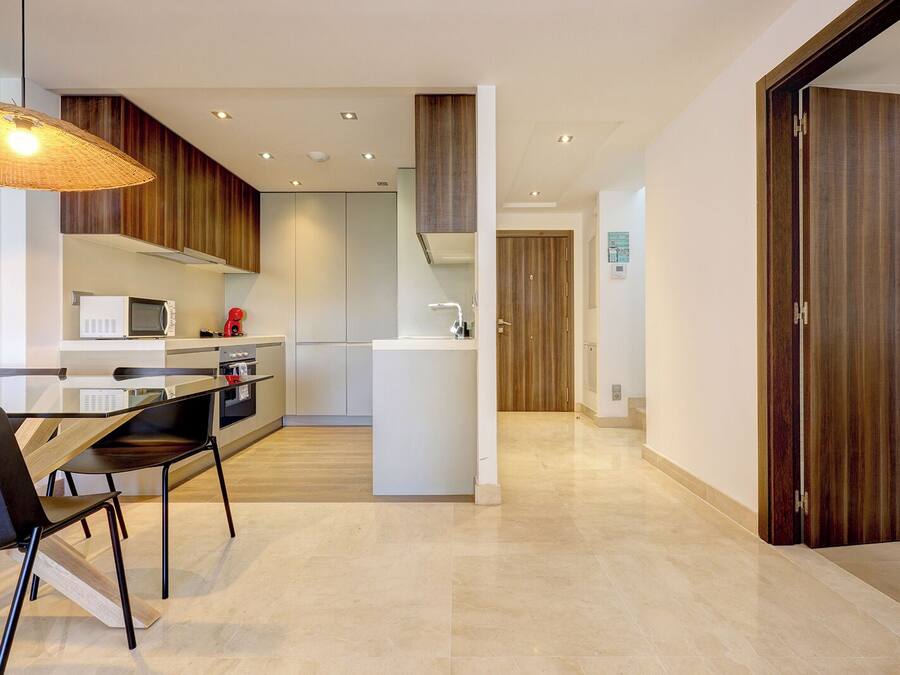 Cozinha moderna com área de jantar, incluindo uma ilha central, eletrodomésticos embutidos e luminária pendente.