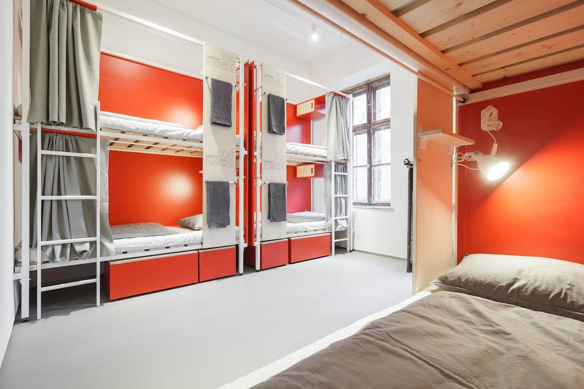 Quarto tipo dormitório com beliches, escrivaninha e janela.