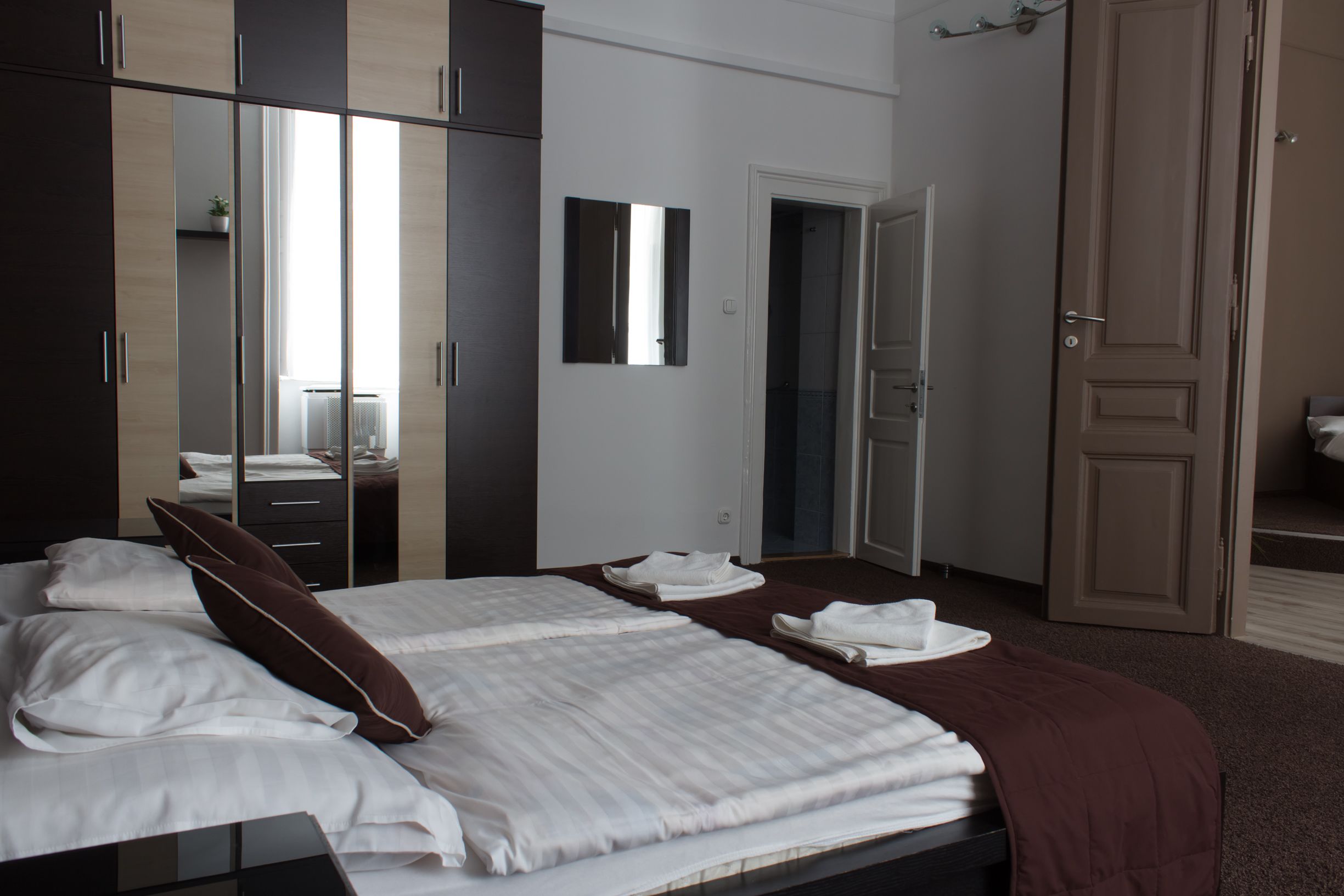 Quarto com uma cama grande, um guarda-roupa, um espelho e uma porta que dá para um banheiro.