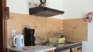 Uma cozinha com cafeteira, chaleira, pia e escorredor de louça.