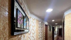 Um corredor com paredes de mármore, uma obra de arte emoldurada e um aviso com a palavra 'WELCOME'.