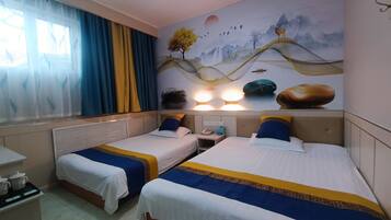 Quarto de hotel com duas camas, mesa de cabeceira, um mural na parede e janela com cortinas.