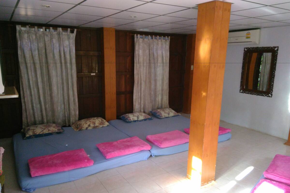 Quarto com uma cama grande, pilares de madeira e um espelho na parede.