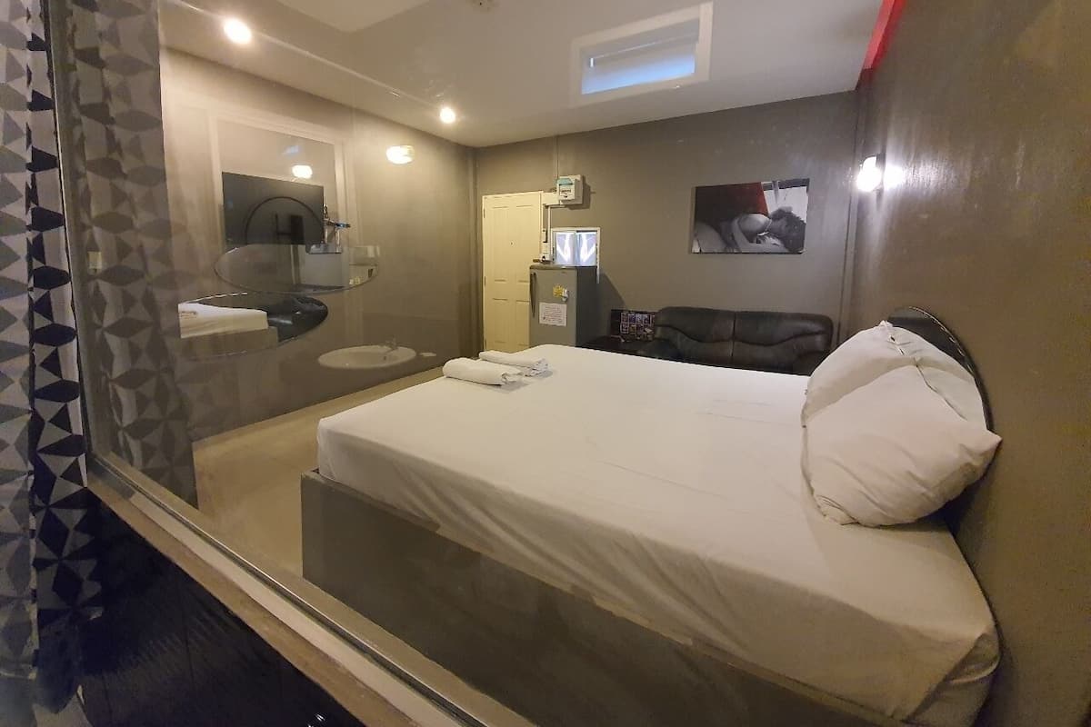 Quarto de hotel com cama, mesa de cabeceira, espelho, janela e televisão na parede.