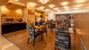 Interior moderno de restaurante com piso de madeira, cadeiras listradas e um balcão de buffet.