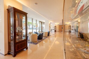 Um hall amplo com um grande armário de madeira, assentos confortáveis e uma mesa de centro de vidro.
