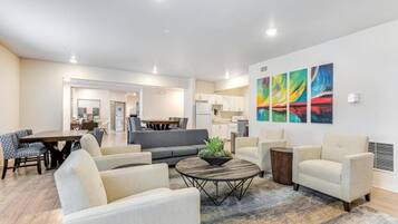 Uma sala de estar moderna com sofá, poltronas, mesa de centro e área de jantar com mesa e cadeiras.