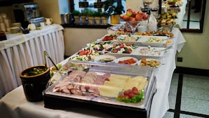 Uma mesa de buffet com diversos alimentos, incluindo carnes, queijos e saladas.