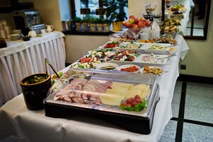 Uma mesa de buffet com diversos alimentos, incluindo carnes, queijos e saladas.