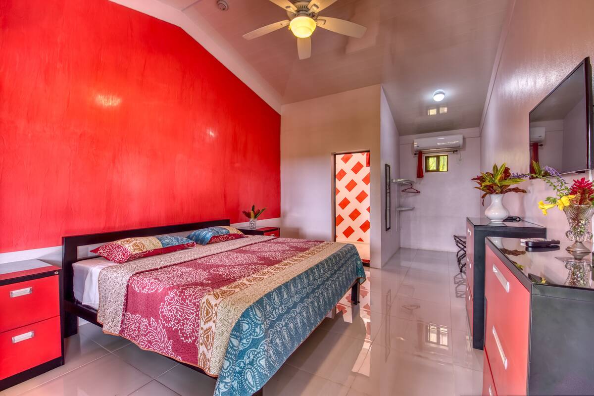Quarto com cama, mesa de cabeceira, cômoda e espelho.
