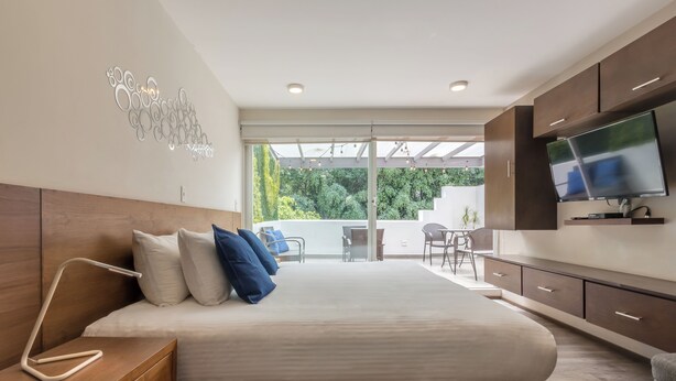 Quarto moderno com uma cama grande, uma TV e vista para o exterior.