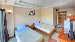 Quarto de hotel com duas camas, uma escrivaninha, televisão e porta do banheiro.