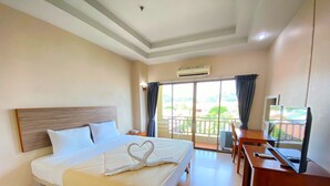 Quarto de hotel com cama grande, escrivaninha, cadeira, televisão e varanda com vista.