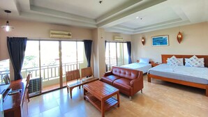 Quarto de hotel com cama, sofá, mesa de centro e televisão.