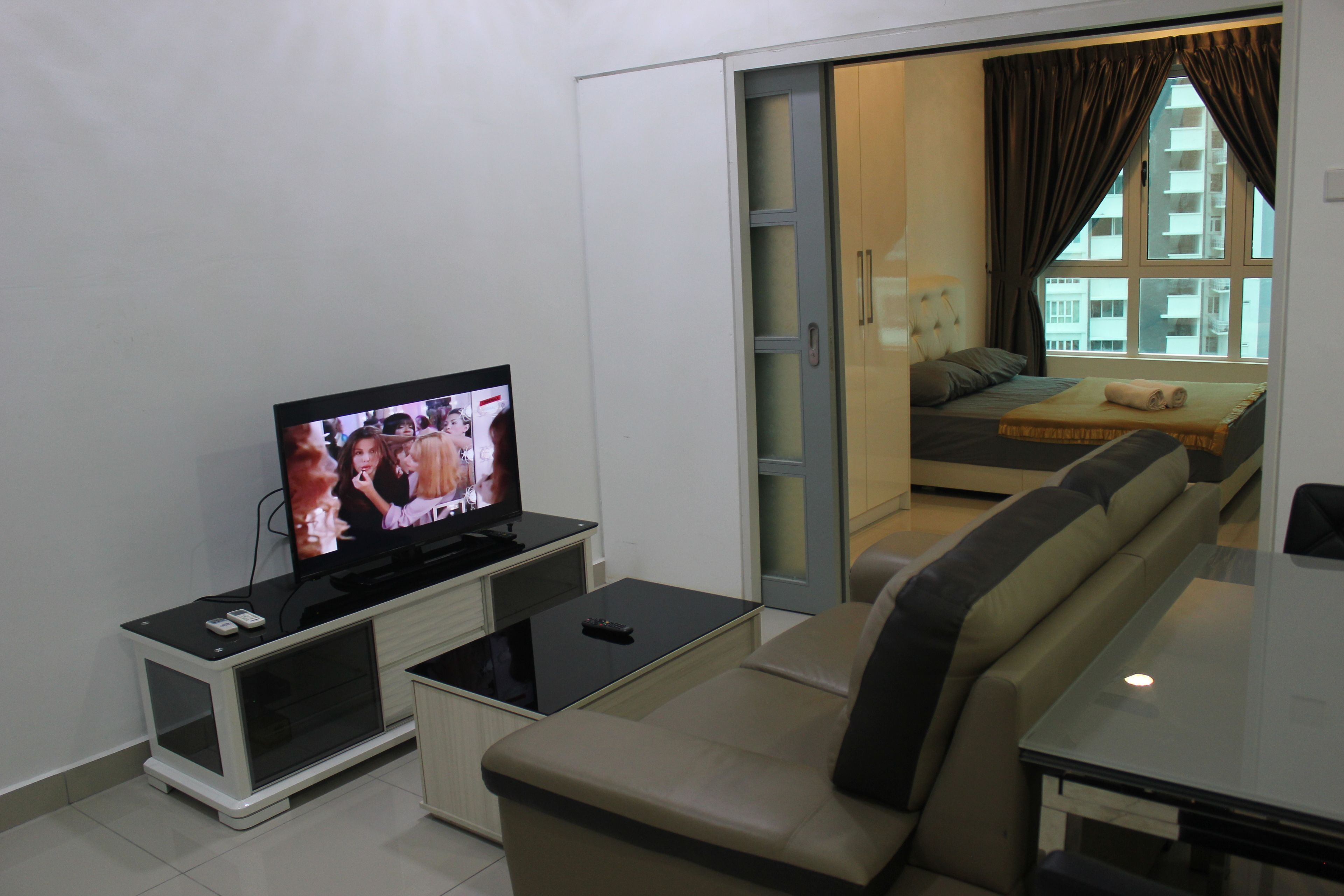 Uma sala de estar moderna com televisão, sofá e porta deslizante que dá para um quarto.