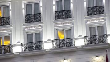 Fachada de edifício com várias janelas e varandas em ferro forjado preto ornamentado.