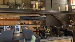 Um interior moderno com área de bar, assentos e escada.