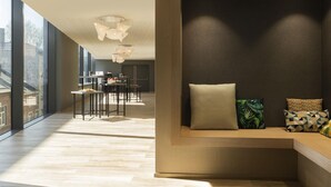 Um interior moderno com área de estar, cozinha ao fundo e grandes janelas.