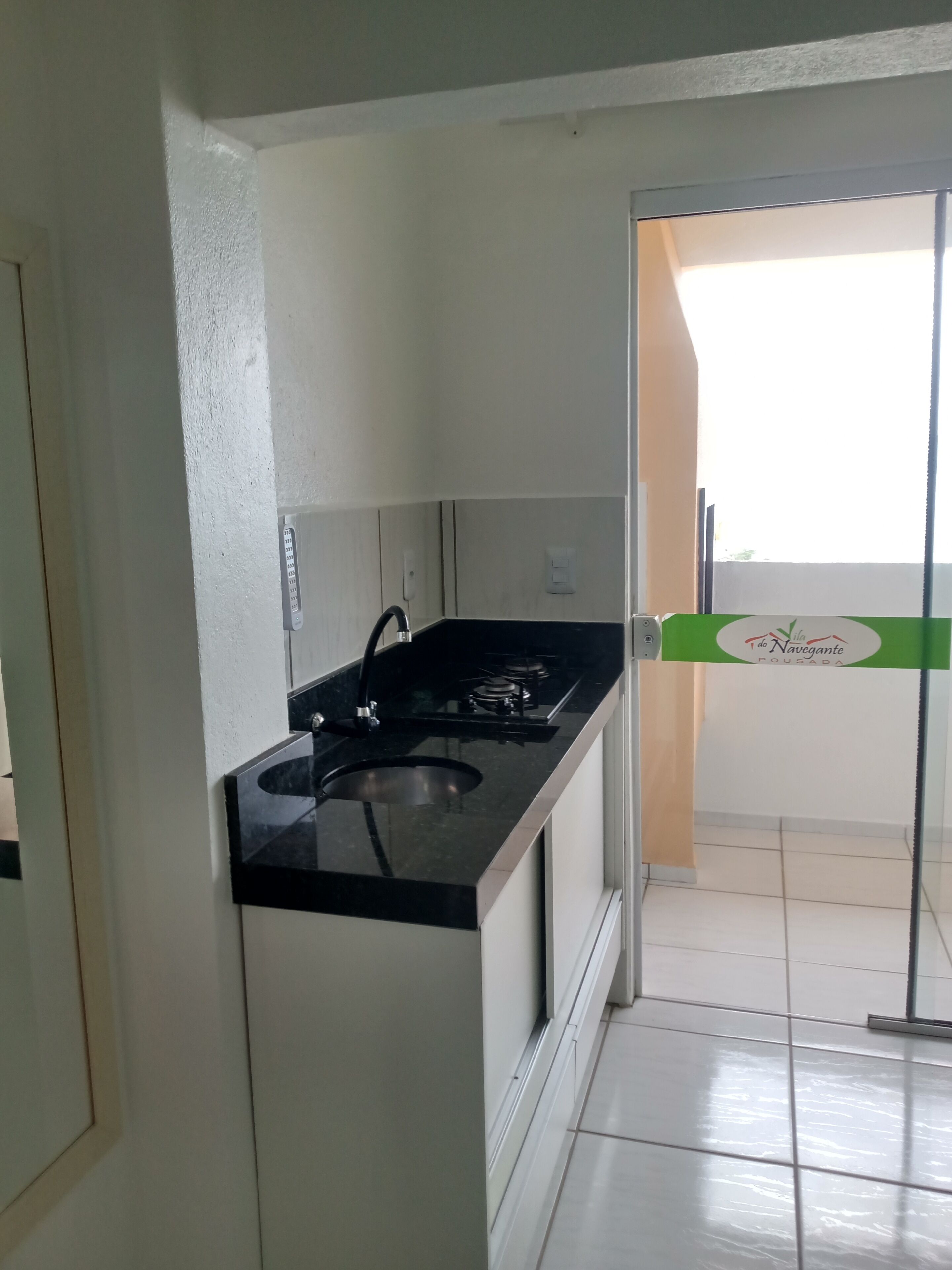 Uma cozinha compacta com bancada preta, armários brancos e uma pia de aço inoxidável.