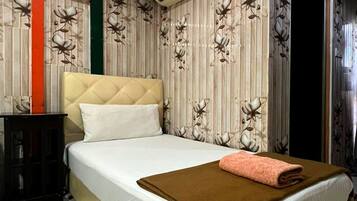 Um quarto com uma cama grande, um ar condicionado acima e uma mesinha de cabeceira com uma luminária.
