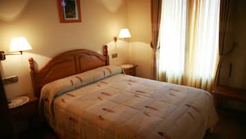 Cama bem arrumada com colcha, duas luminárias de cabeceira e um quadro na parede.