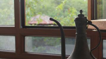 Um vaso num peitoril com vista para vegetação e um edifício lá fora.