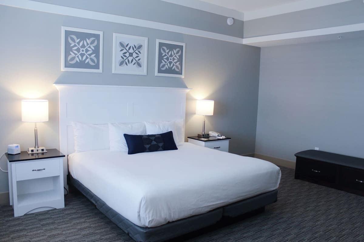 Quarto de hotel com cama grande, duas mesas de cabeceira, escrivaninha e cômoda.