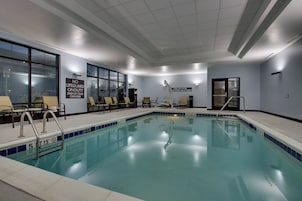 Piscina com cadeiras de descanso, placa indicando ausência de salva-vidas e aviso de mergulho permitido em águas rasas.