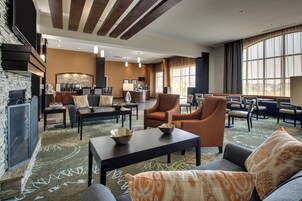Um hall de hotel com lareira, área de estar e um canto para café.
