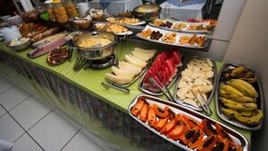 Buffet com diversos alimentos, incluindo frutas, legumes e carnes.