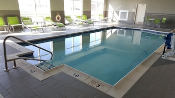 Piscina interior com água cristalina, linhas de profundidade marcadas e uma escada de piscina.