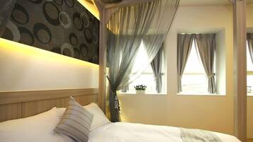 Quarto de hotel com uma cama, parede com padrões circulares e duas janelas com cortinas.