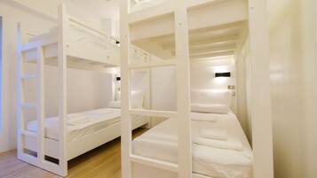 Quarto com beliches, piso de madeira e decoração em tons de branco.