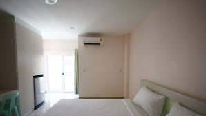 Quarto de hotel com uma cama, uma cadeira verde e um aparelho de ar condicionado na parede.