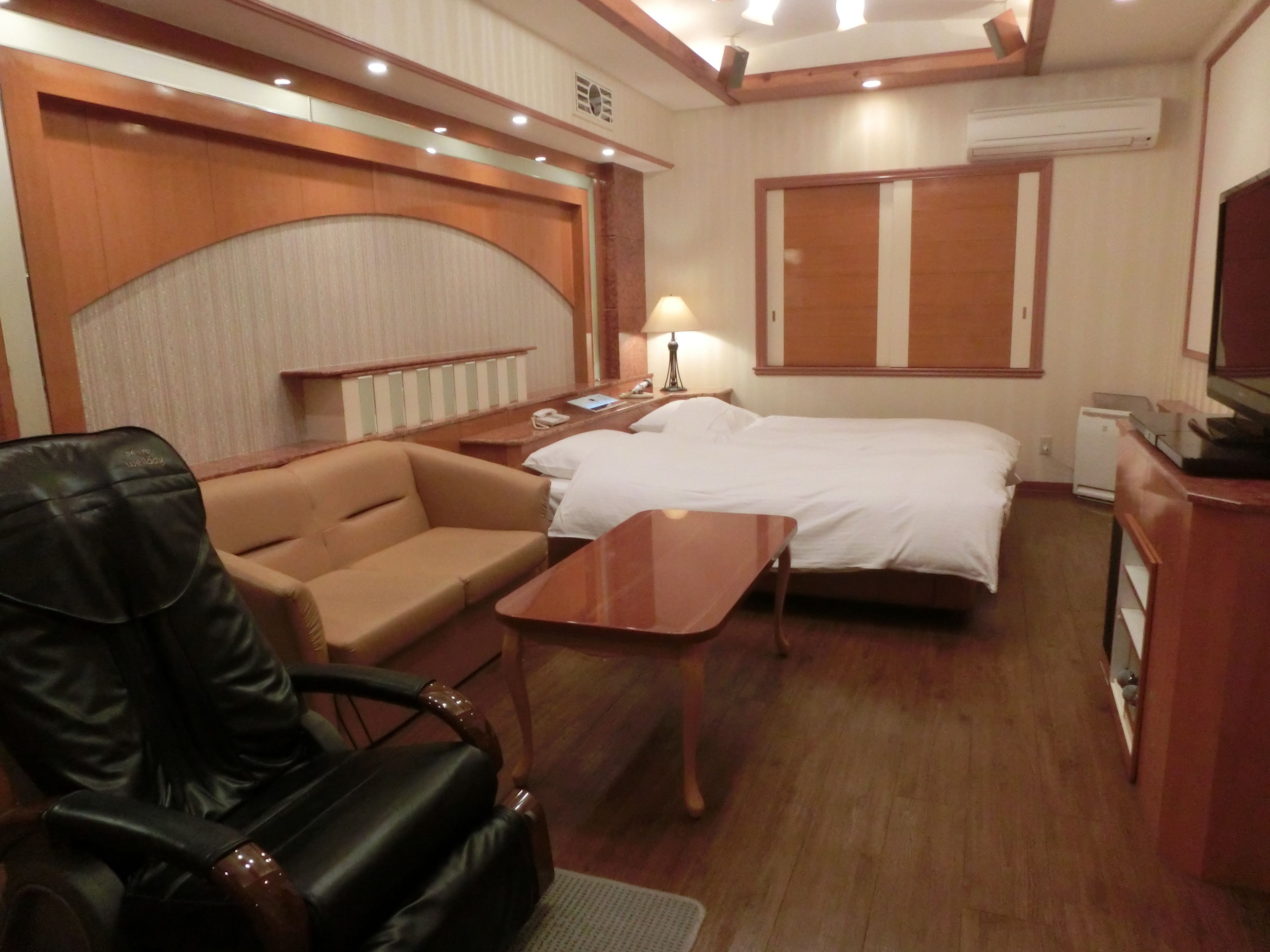 Quarto de hotel com cama, escrivaninha, cadeira e ar condicionado.