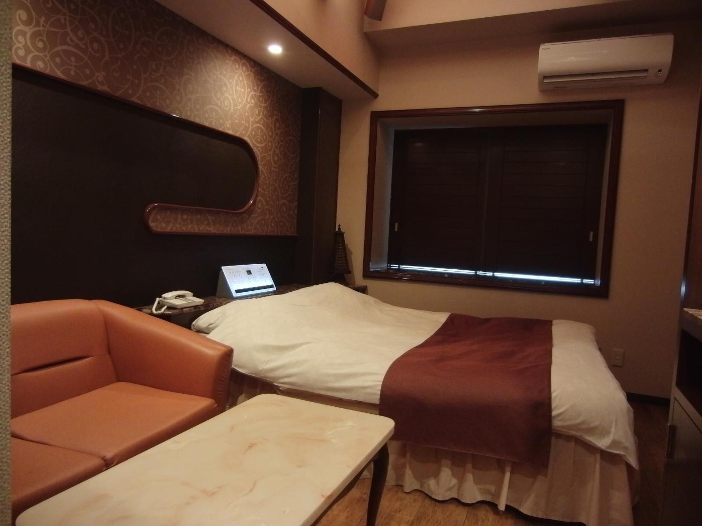 Quarto de hotel com cama, escrivaninha, cadeira, laptop e ar condicionado.