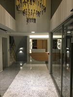 Um lobby moderno com balcão de recepção, escada e decoração de teto singular.