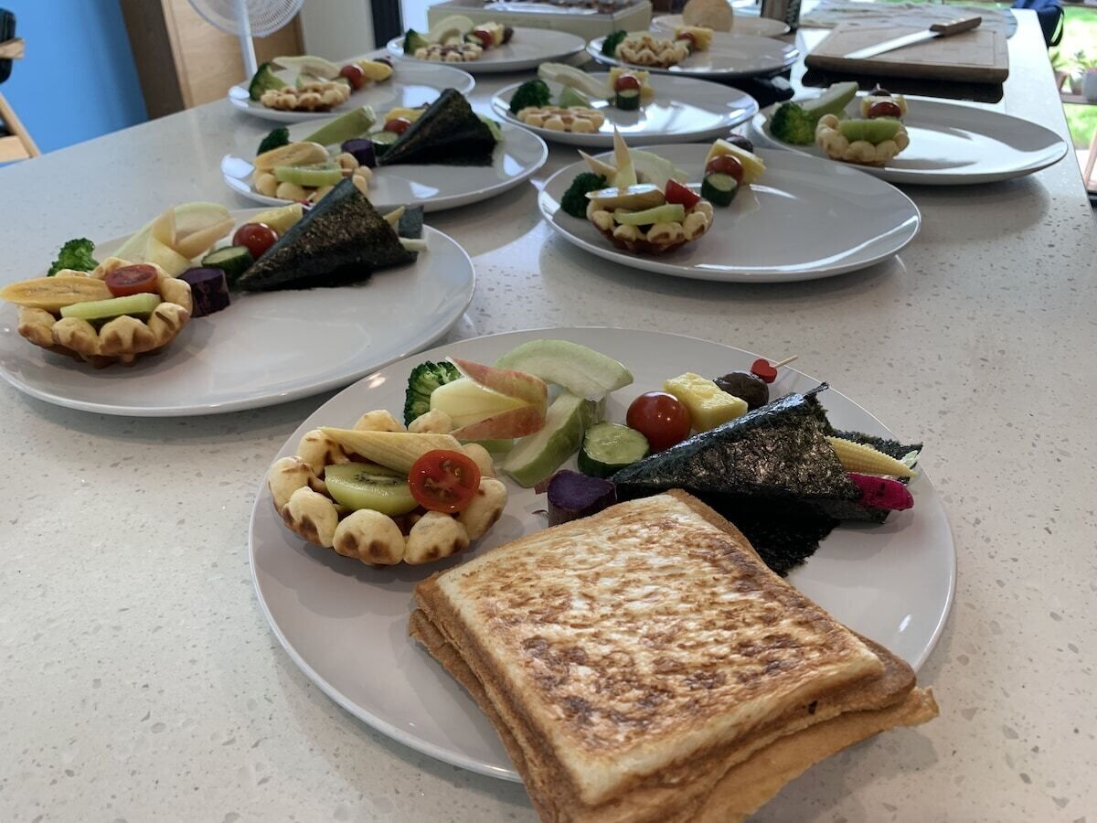 Uma mesa com diversos pratos servidos, incluindo sanduíches, legumes e pequenos aperitivos.